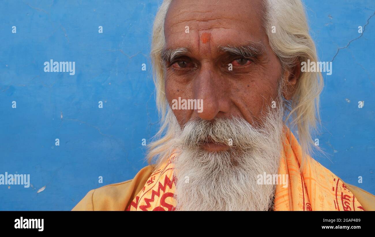 A religious ascetic Sadhu in traditional Indian clothes sitting outdoor ...