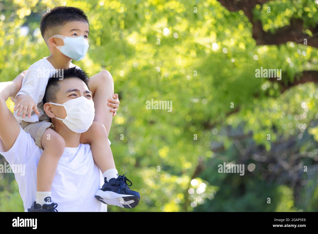 Father wearing face mask while playing a piggyback ride with his son in ...