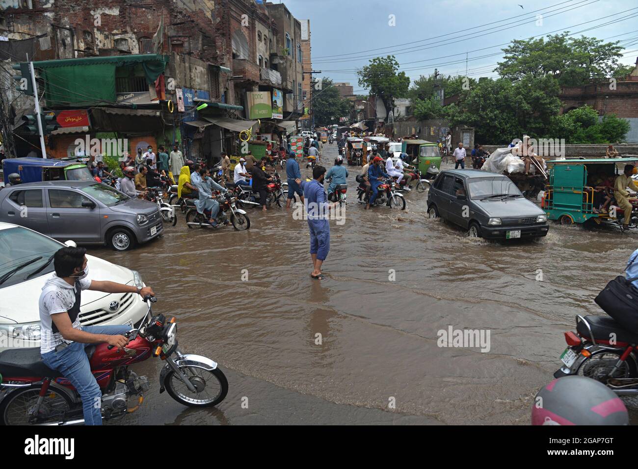 Lahore, Pakistan. 31st July, 2021. Pakistani commuters wade through a ...