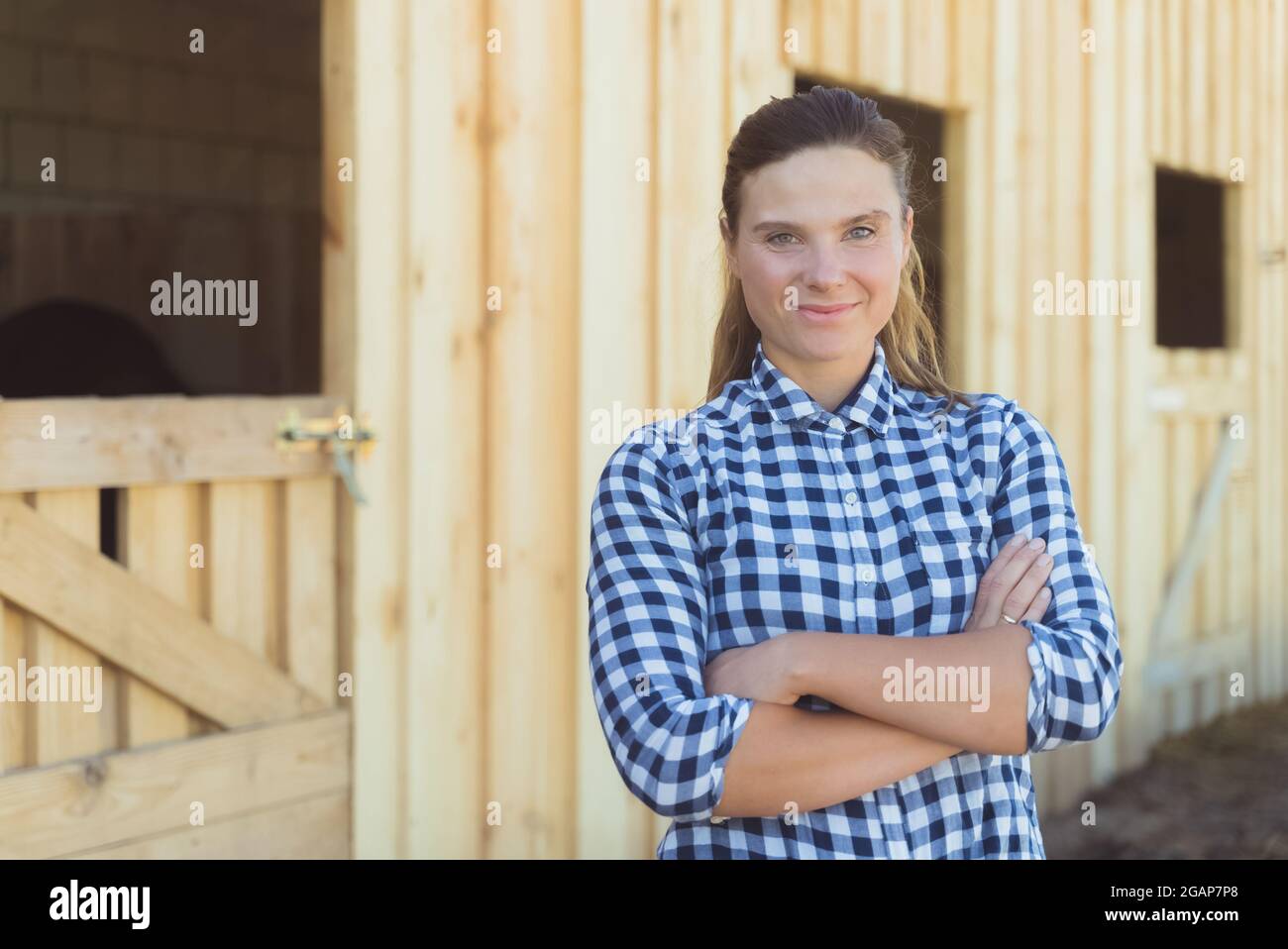 Girl standing outside the horse stable with rows of stall windows ...
