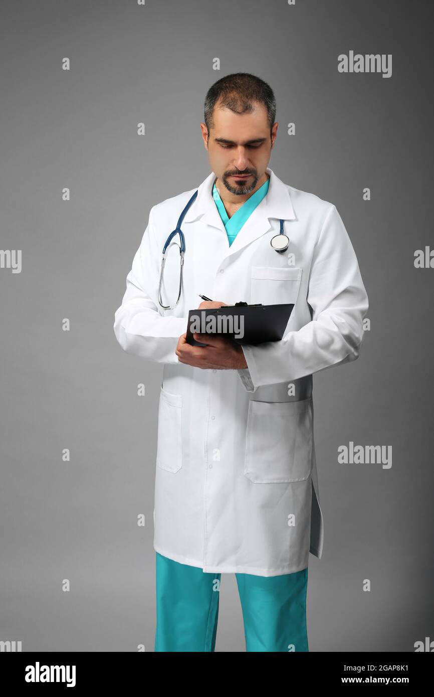 Portrait of a doctor with prescription board in hands on grey ...
