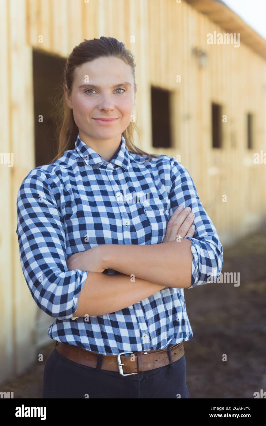 Girl standing outside the horse stable with rows of stall windows ...