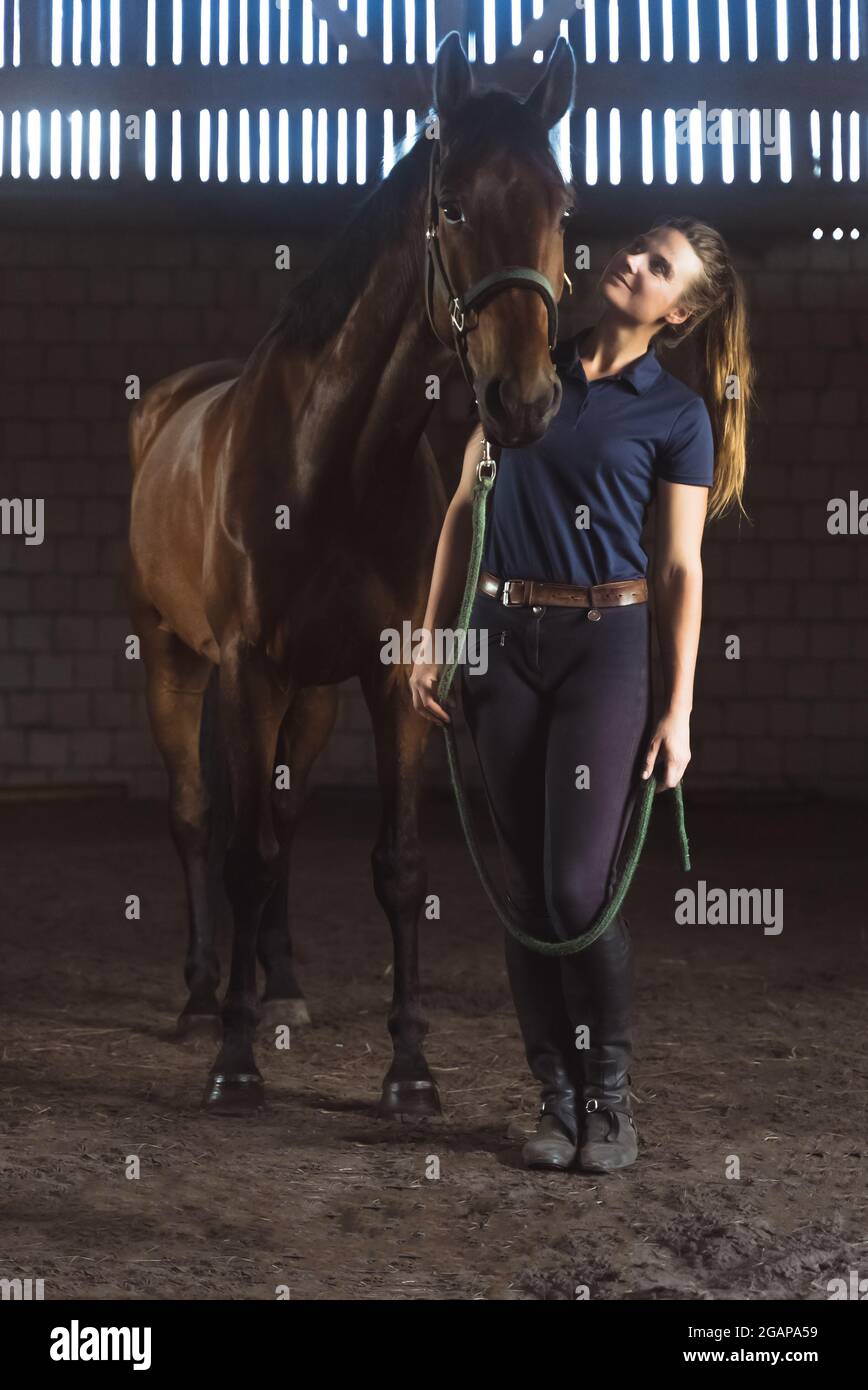 Horsewoman looking at her seal brown horse with love in the stable ...