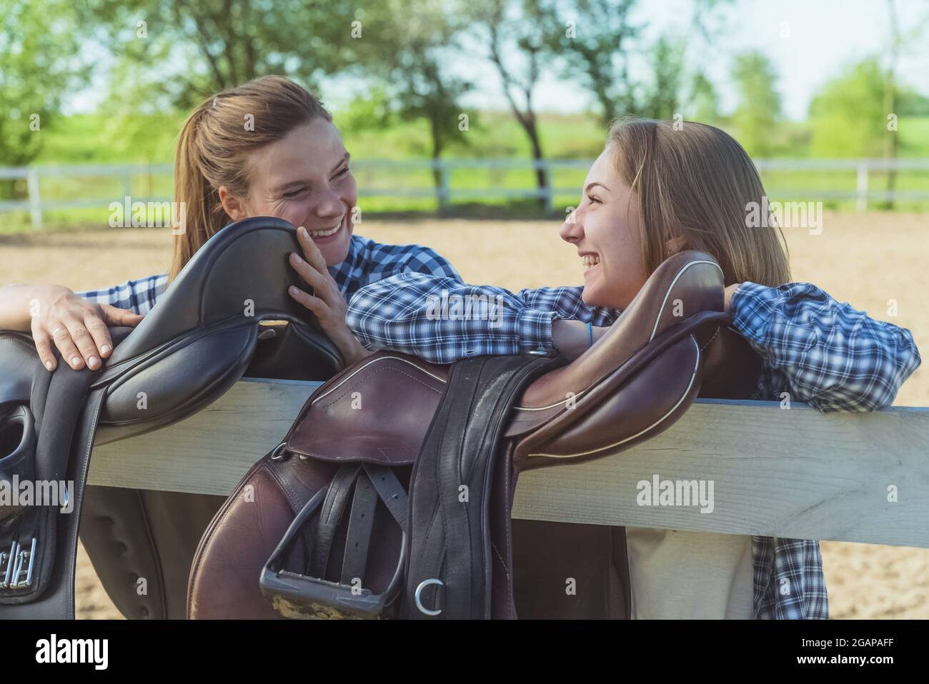 Two young girls standing with their hands resting on the wooden fence ...