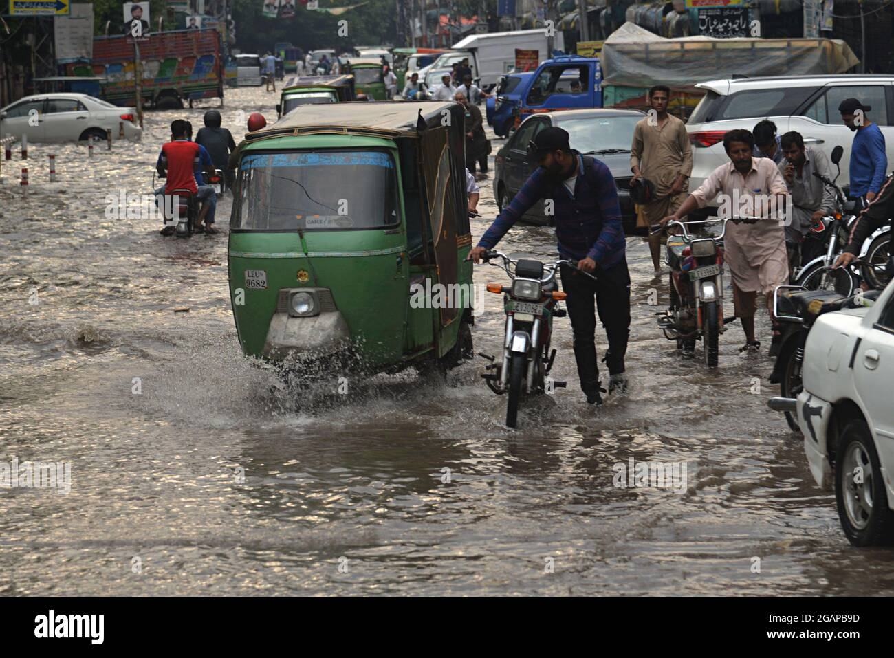 Pakistani commuters wade through a flooded street after heavy monsoon rain spell in provincial ...