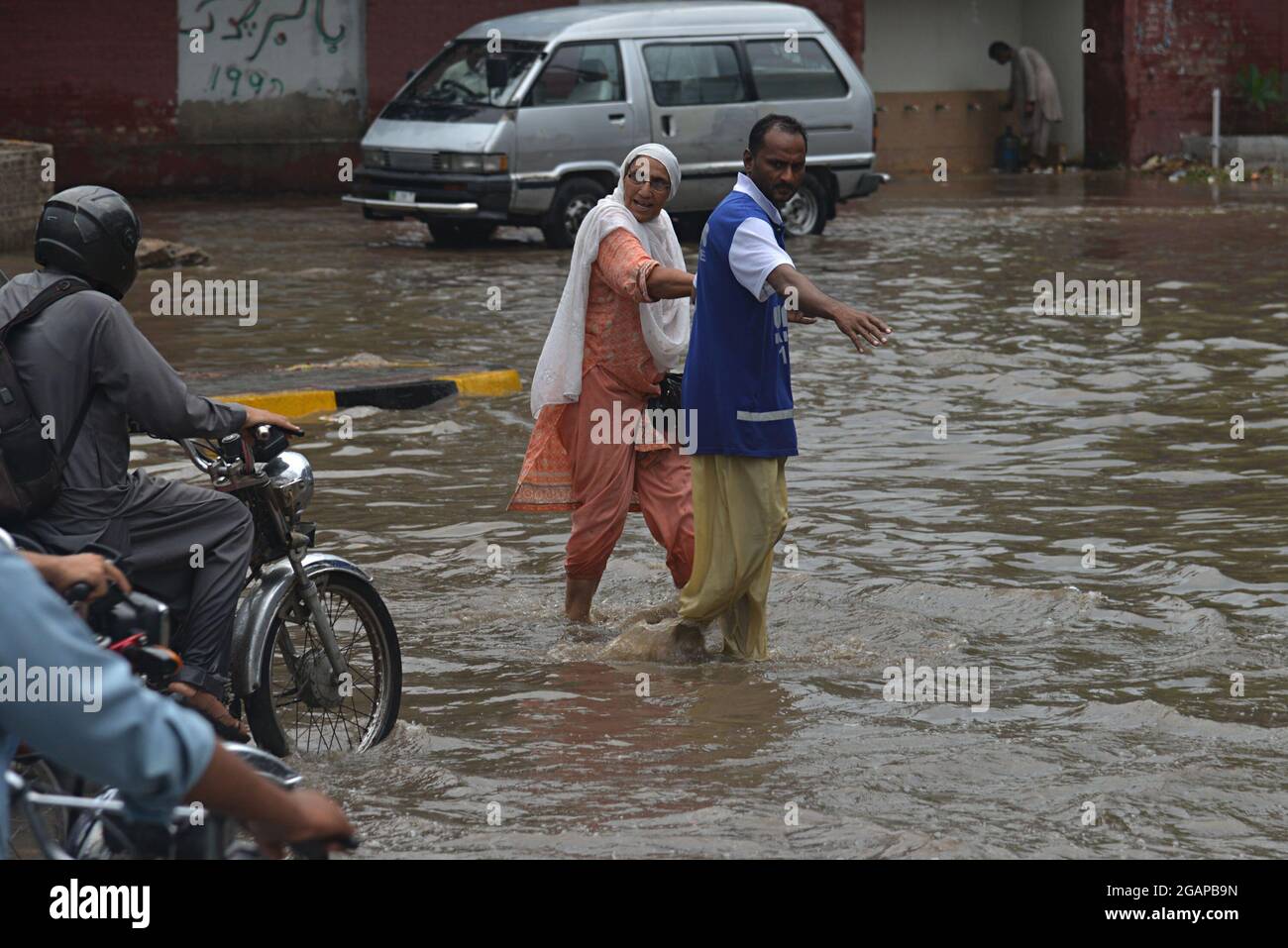 Pakistani commuters wade through a flooded street after heavy monsoon rain spell in provincial ...