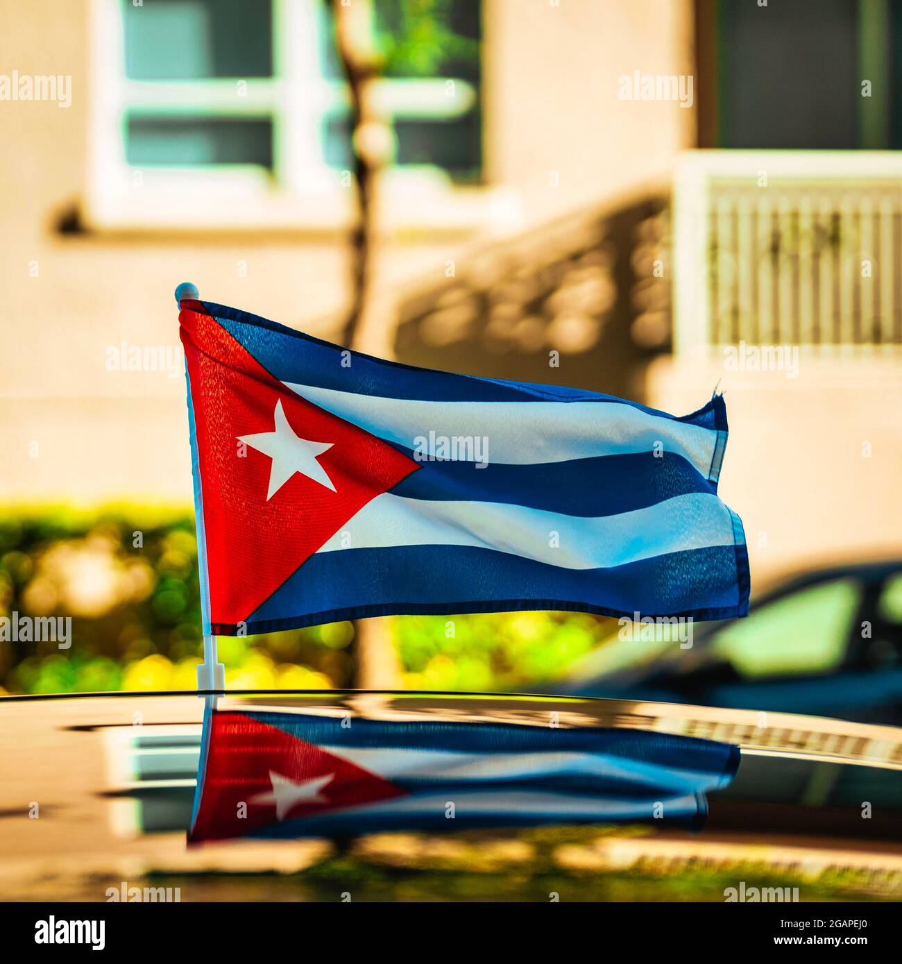 The flag of Cuba flapping in the wind on a car roof with its reflection ...
