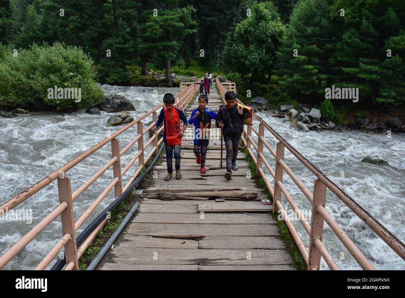 Kashmiri nomad children walk through a wooden foot-bridge during a ...