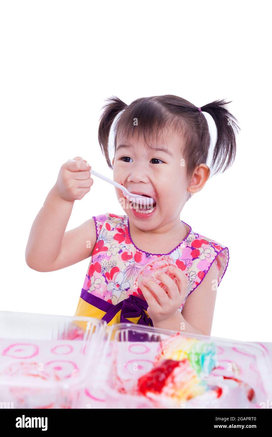 Adorable little asian (thai) girl enjoy eating her birthday cake at the ...