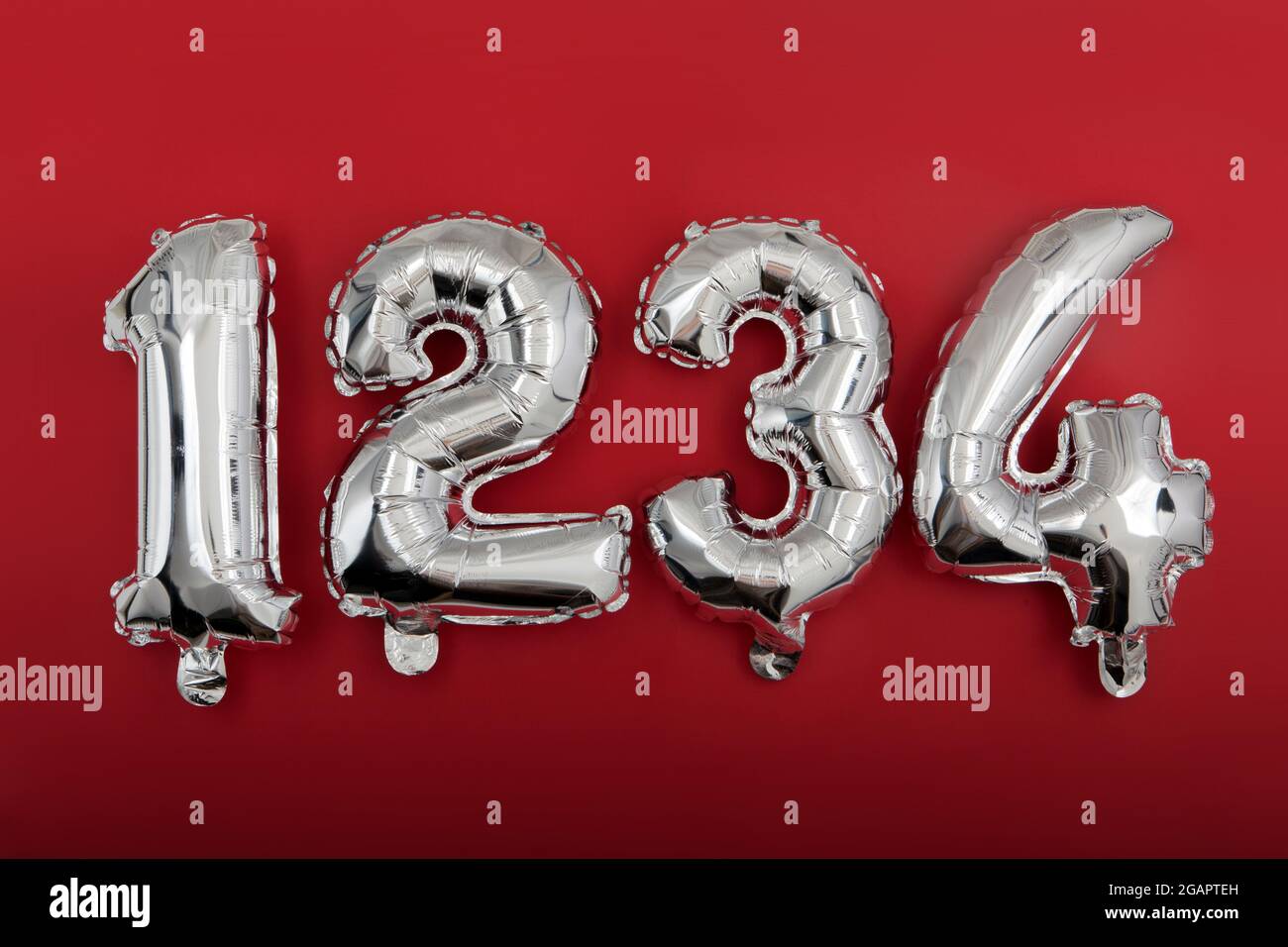 Top view of shiny silver number balloons arranged in row from 1 to 4 on ...
