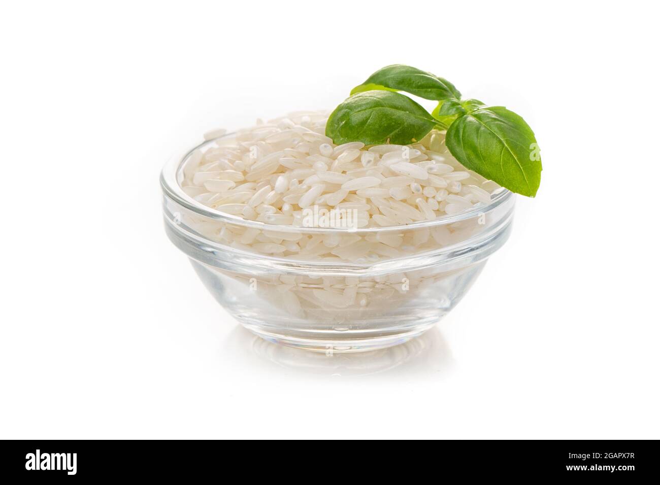 Raw white rice in a clear glass plate decorated with basil leaf on a ...