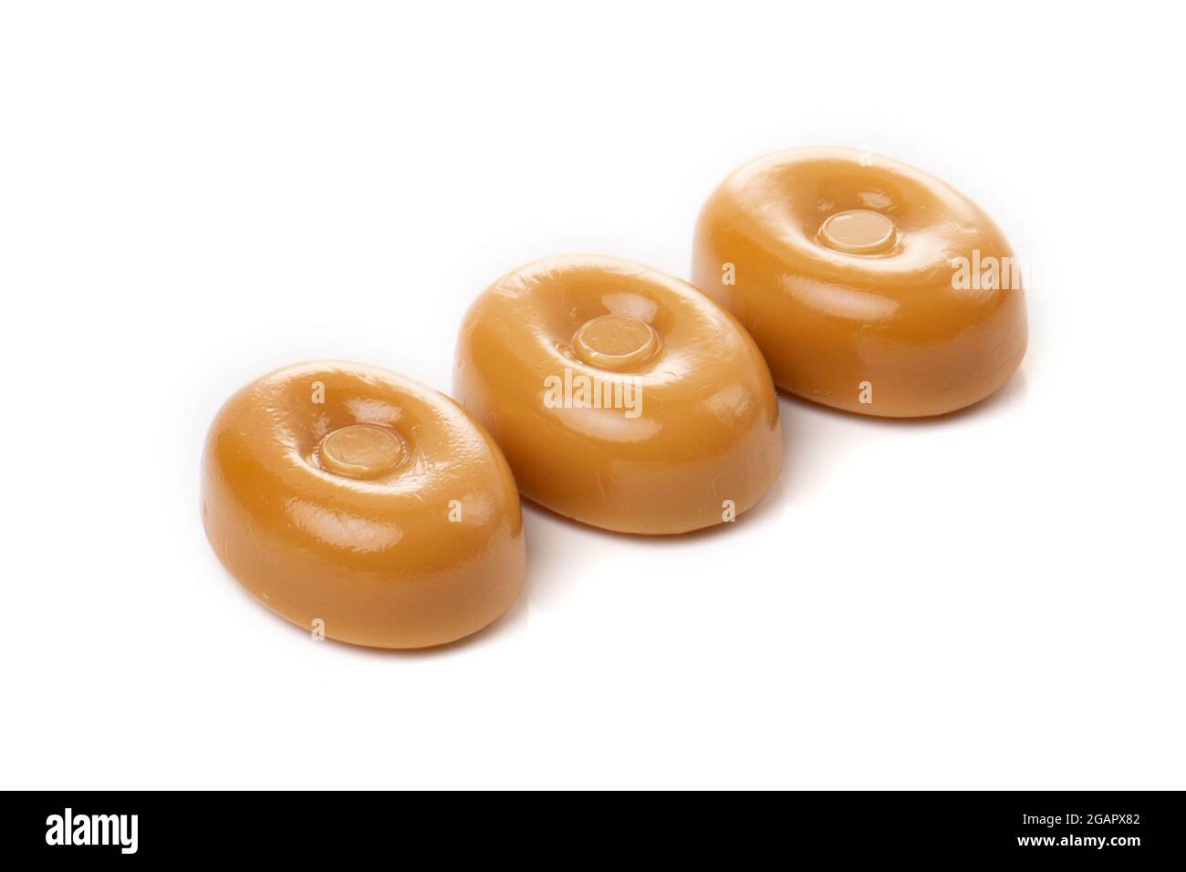 Three caramel candies on a white background close-up Stock Photo - Alamy