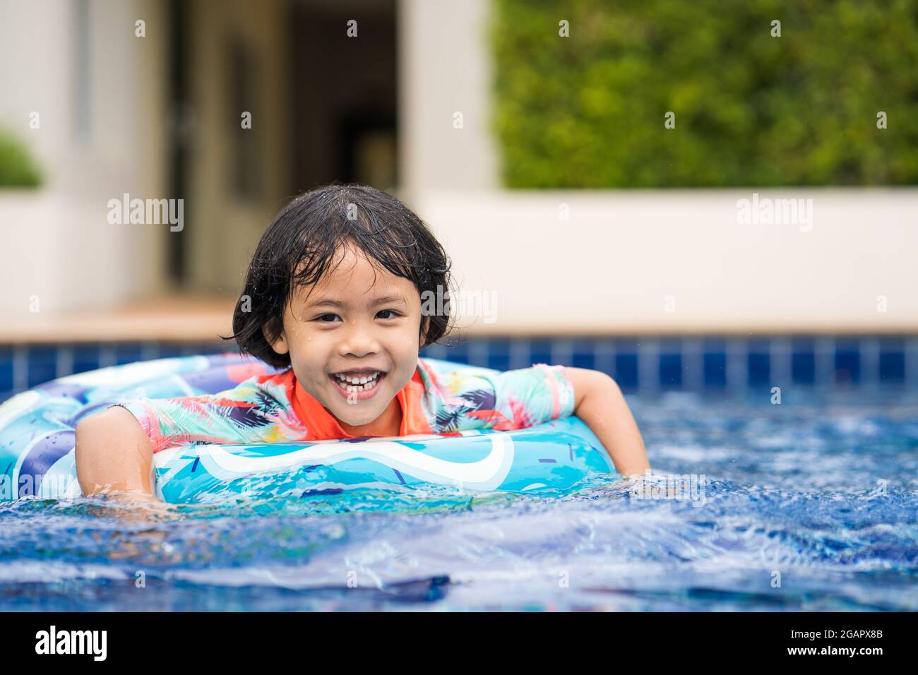 A cheerful Asian female kid in a ring floater on swimming pool Stock ...
