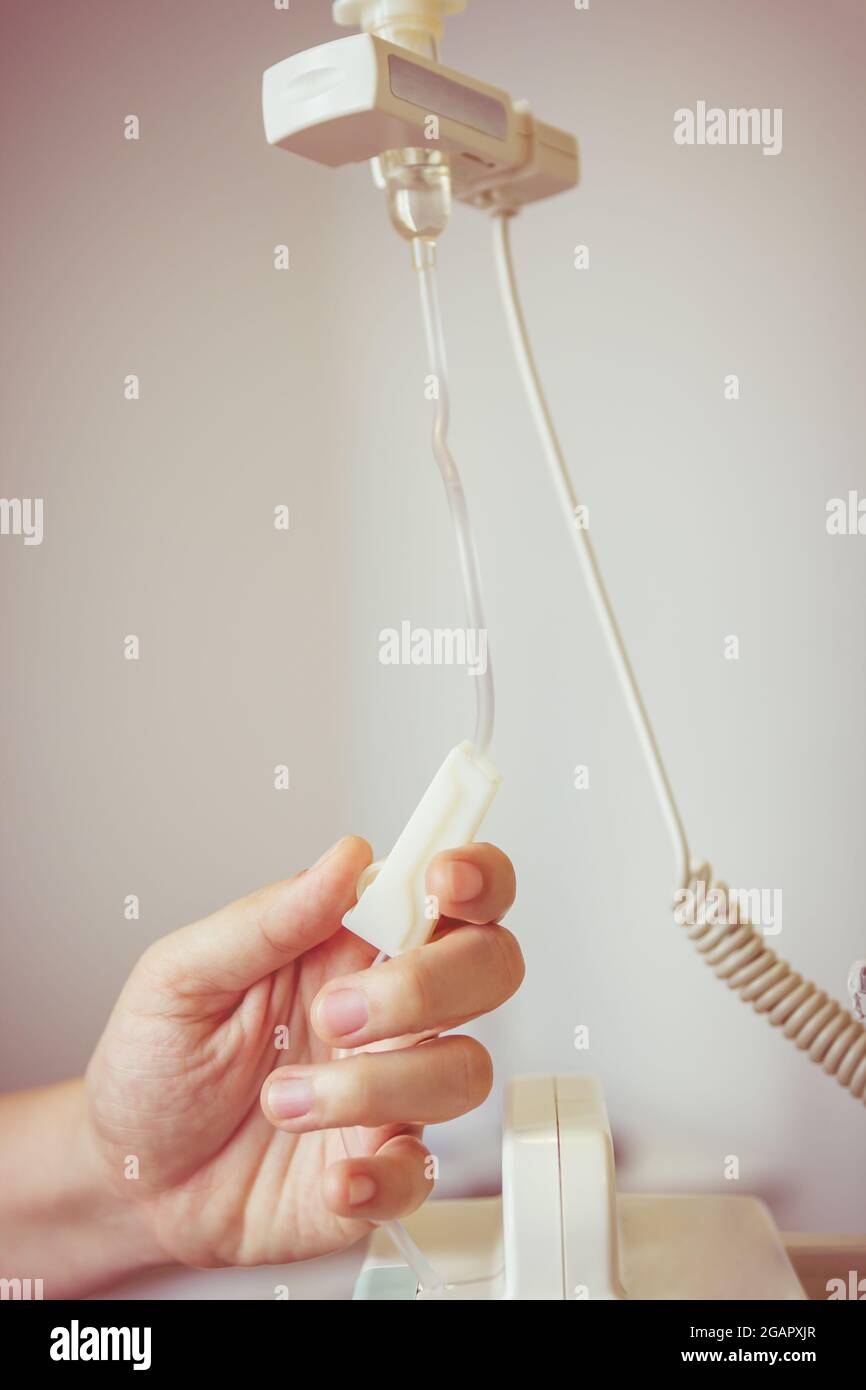 Nurse's hands regulation an intravenous (IV) drip in hospital room ...