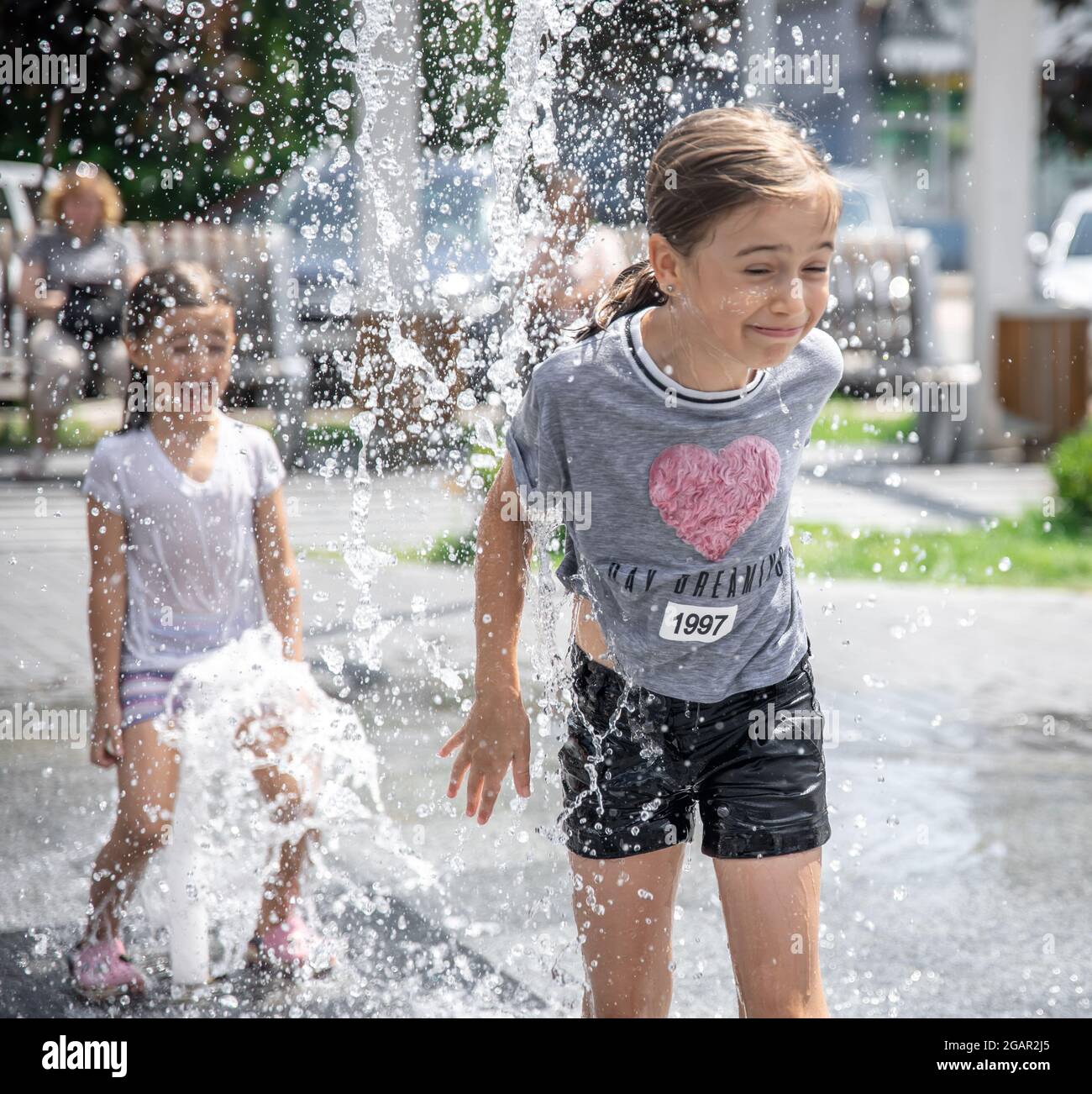 Little girls cool off in a fountain on a hot summer day Stock Photo - Alamy