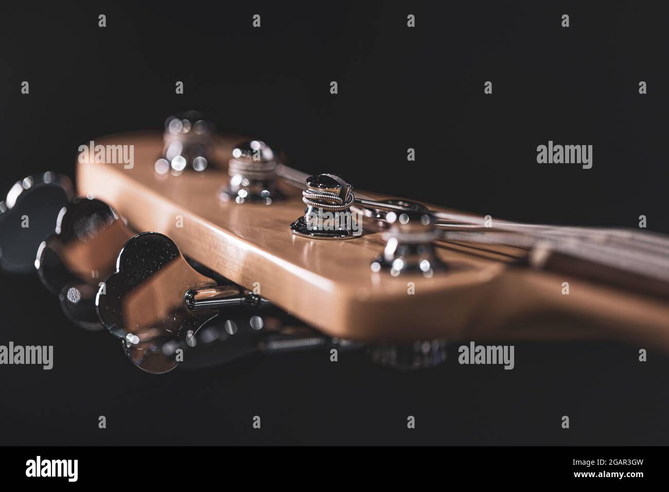 Detail of a tuning post on the wooden headstock of an electric bass ...