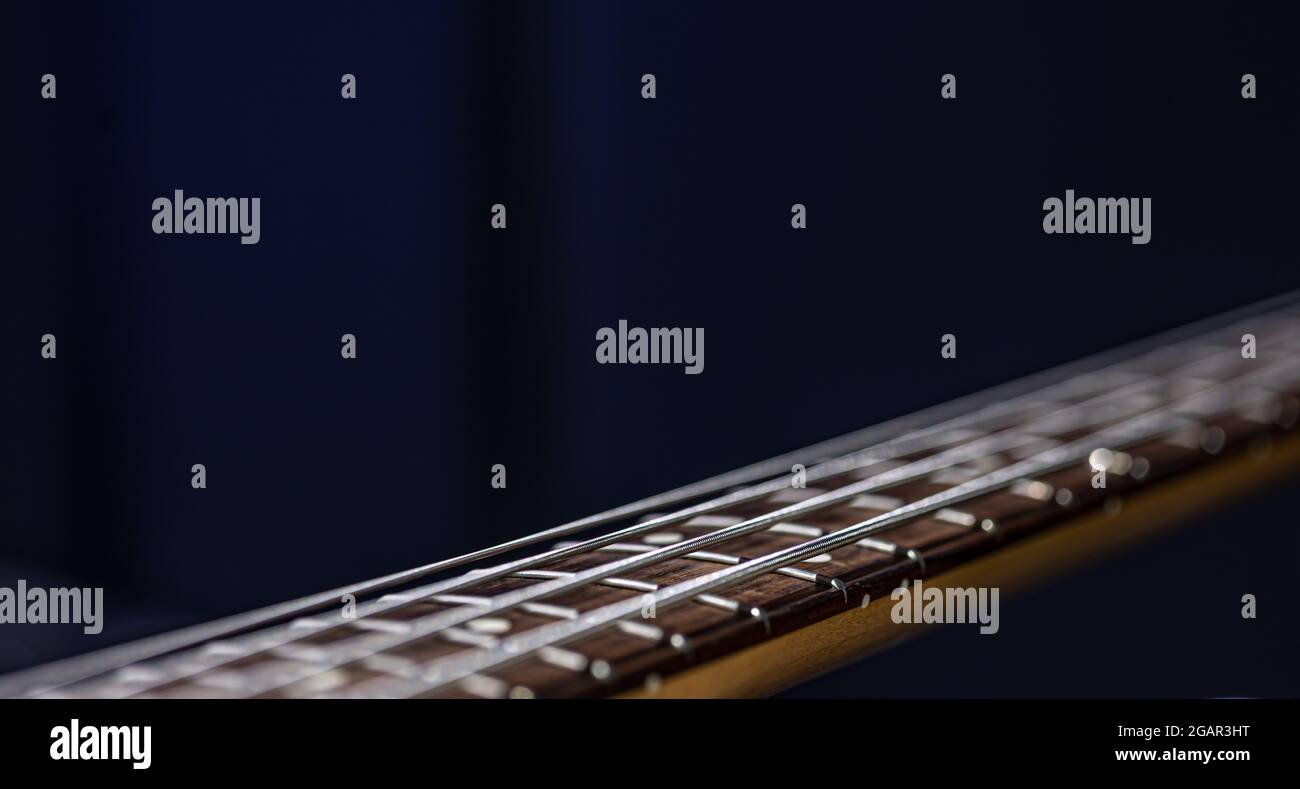 Close up of strings on bass guitar on blurred black background copy ...