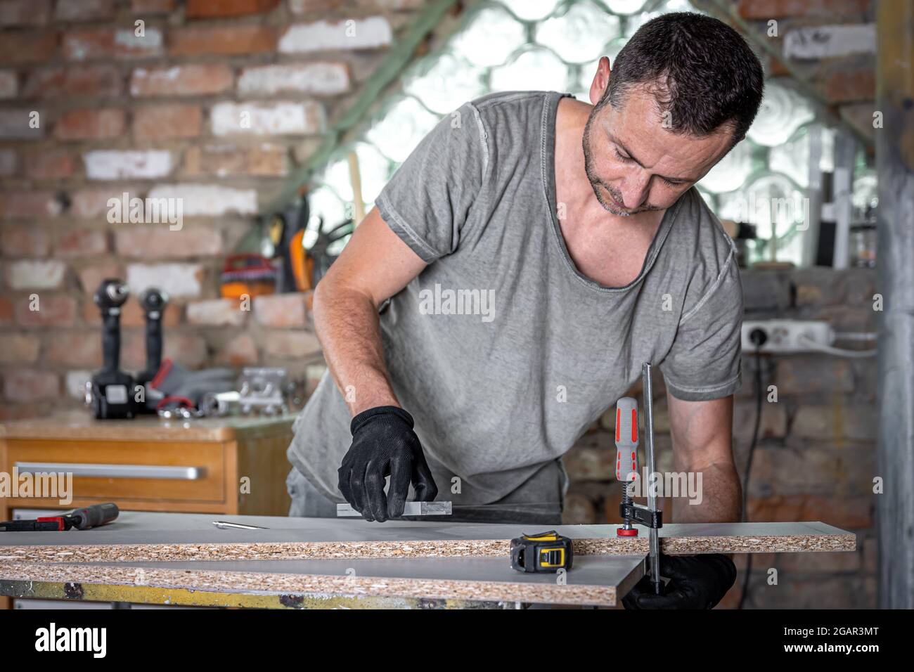 Carpenter doing wood work using clamping hand tool in his workshop ...