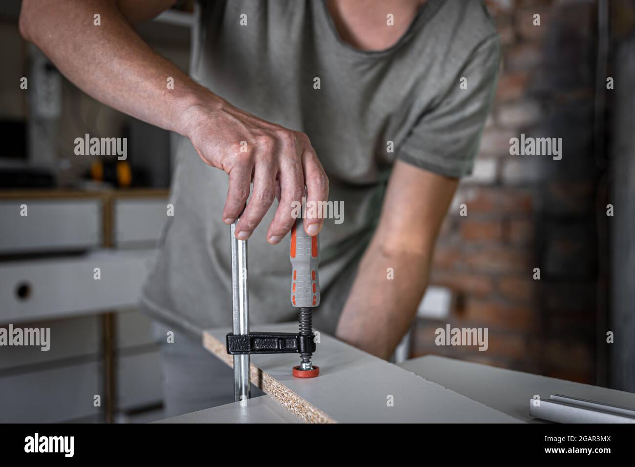 Carpenter doing wood work using clamping hand tool in his workshop ...