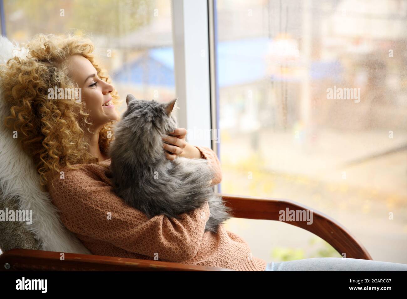 Young woman and cat beside window in the room Stock Photo - Alamy