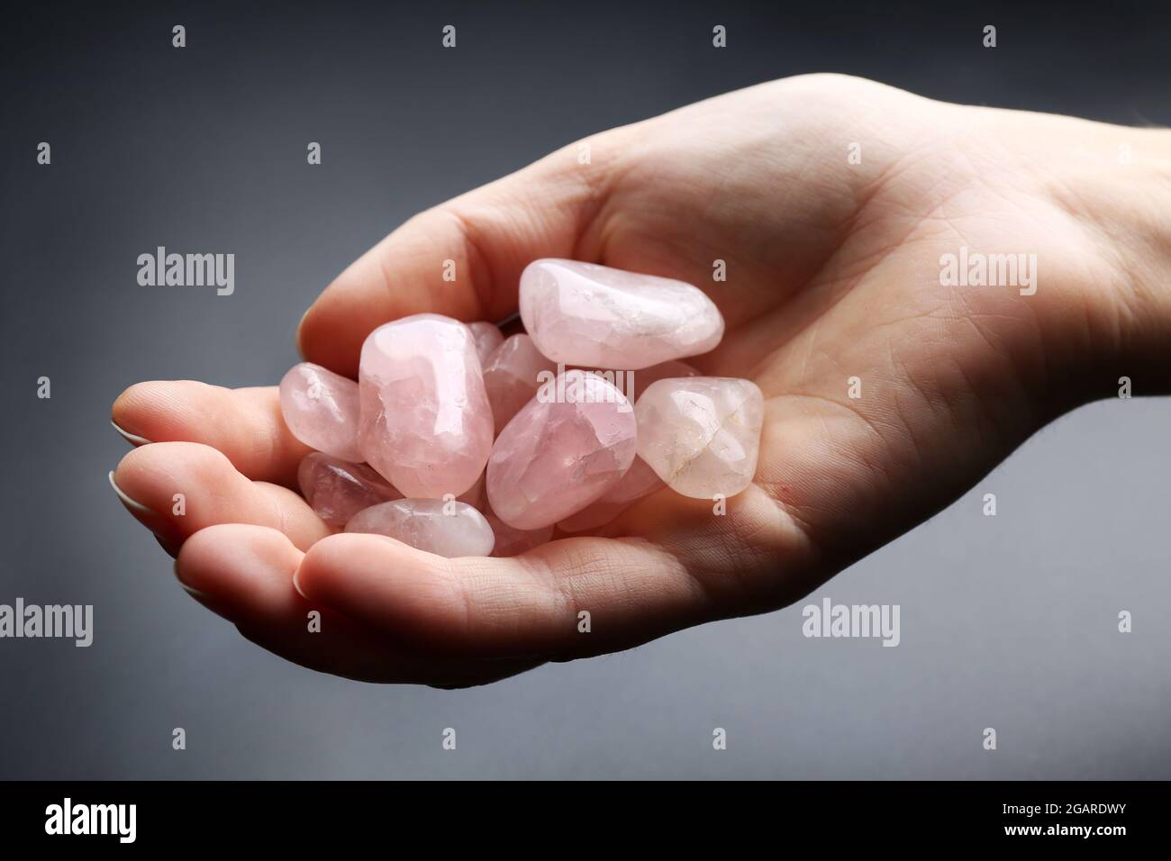 Woman holding semiprecious stones in her hand on dark grey background ...