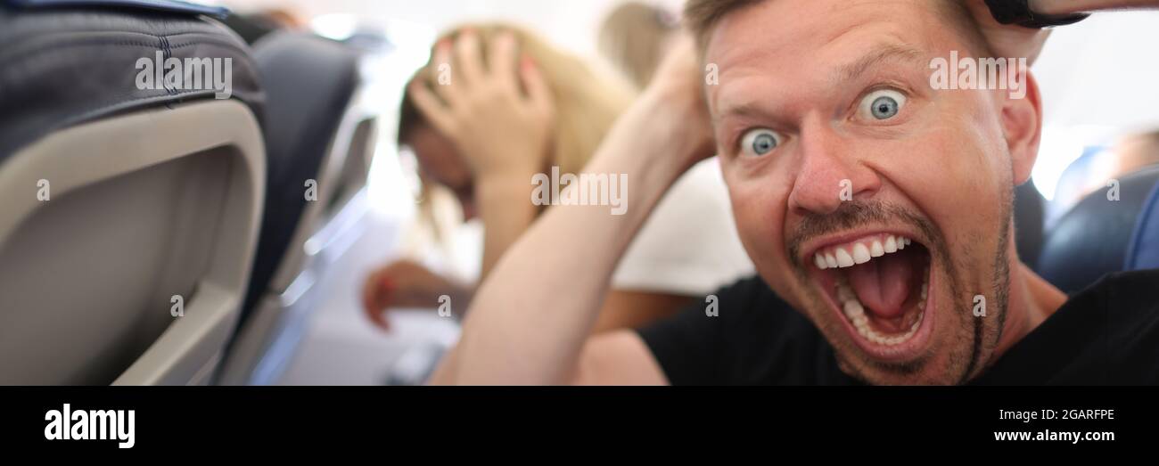 Male passenger holding his head and shouting on plane Stock Photo - Alamy