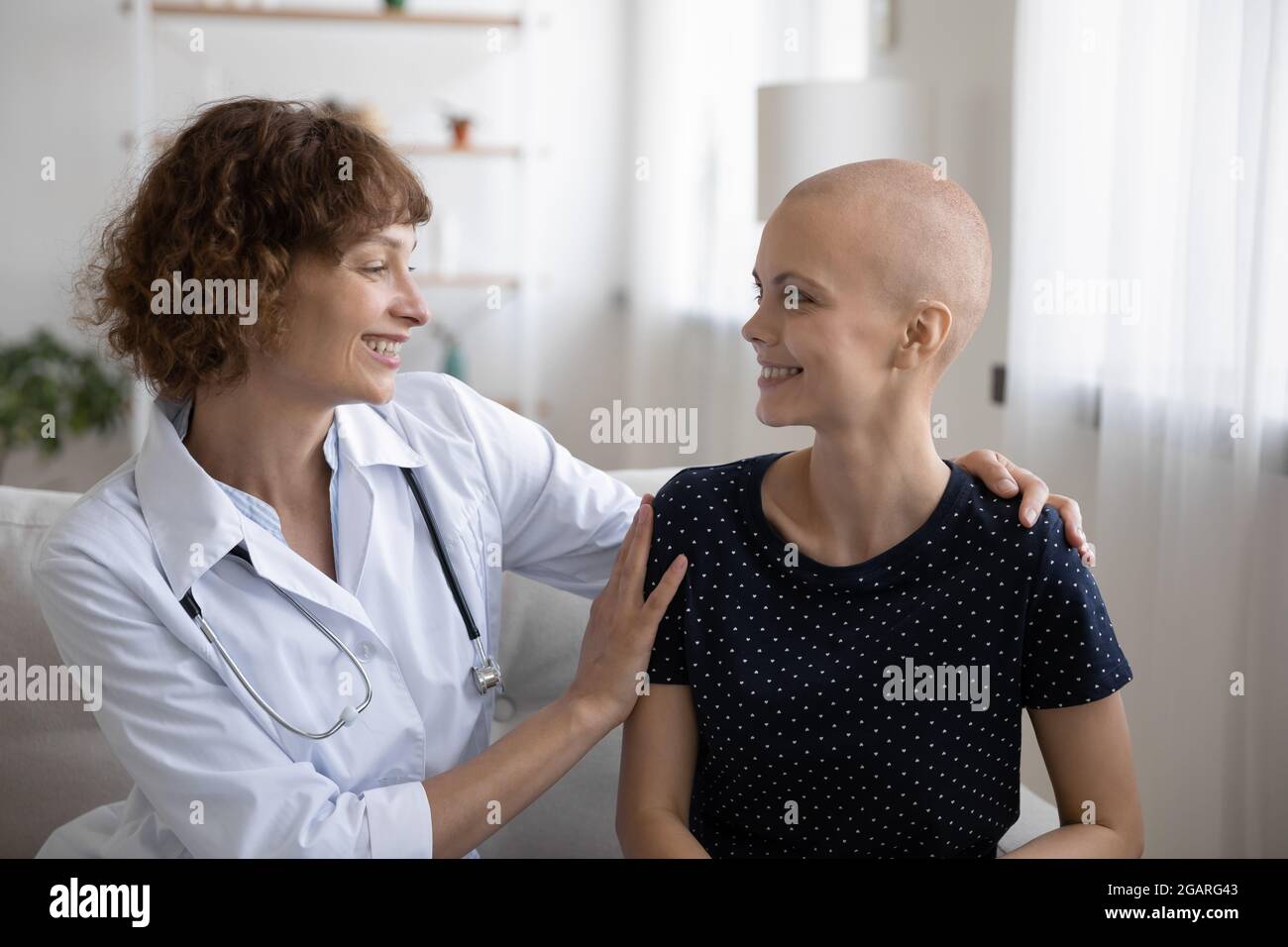 Happy young female doctor supporting bald patient Stock Photo - Alamy