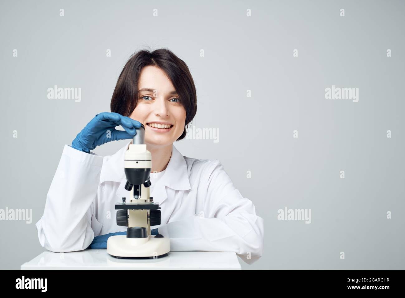 female laboratory assistant looking through a microscope diagnostics ...