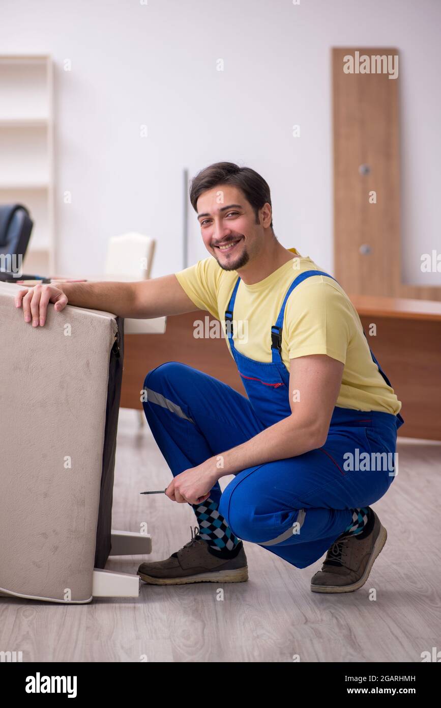 Young carpenter repairing arm-chair in the office Stock Photo - Alamy