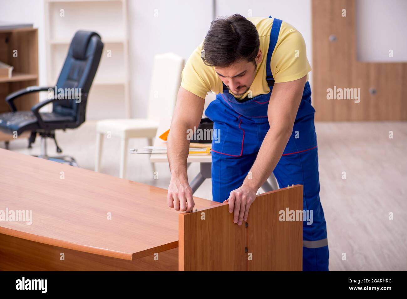 Young carpenter repairing desk in the office Stock Photo - Alamy