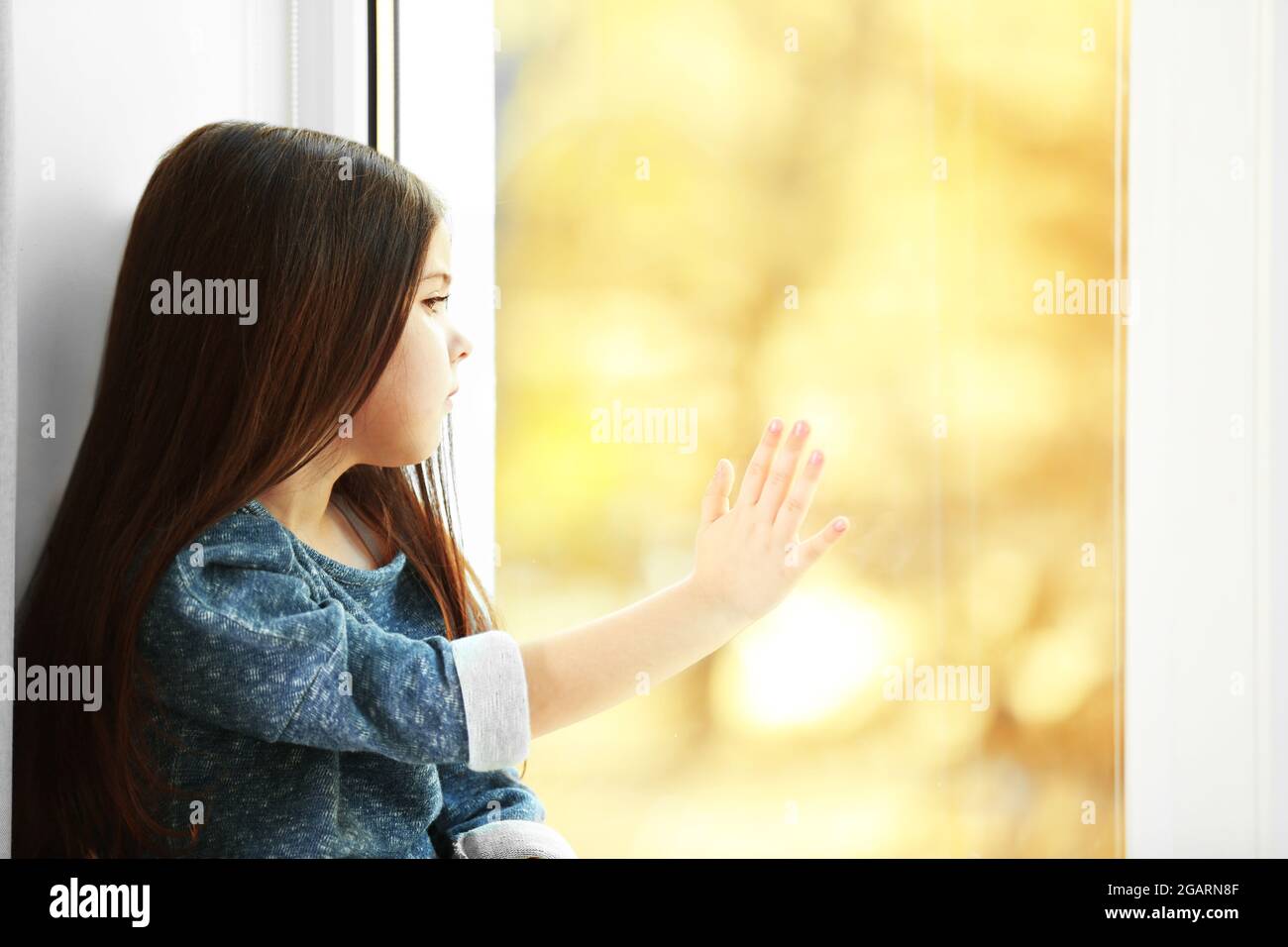 Little girl waiting for someone and looking out the window Stock Photo ...