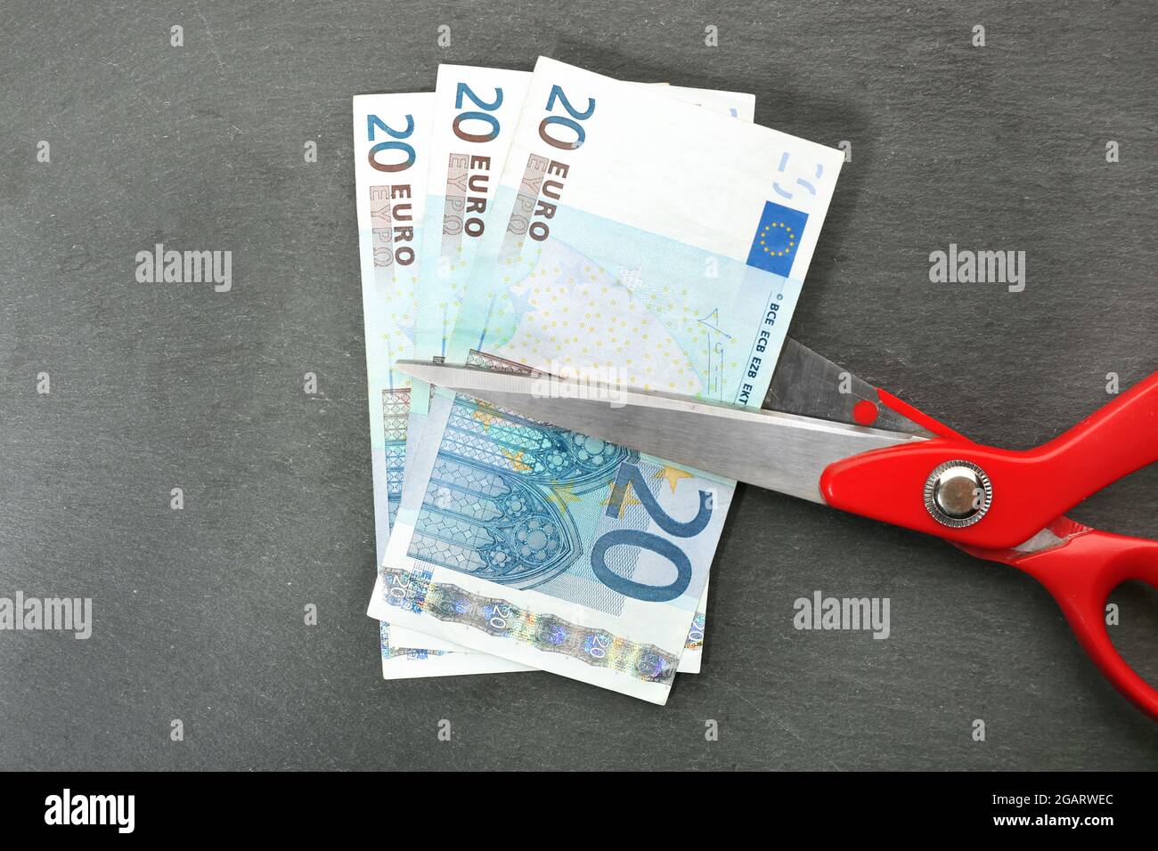 Red scissors cut money on black background. Financial concept Stock ...
