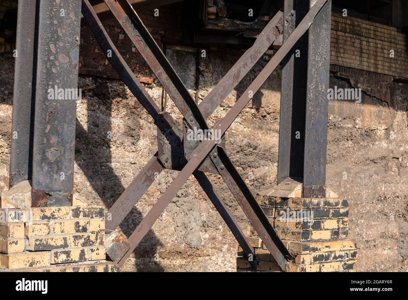 Brick and aggregate wall behind piers and rusty steel I-beam supports ...
