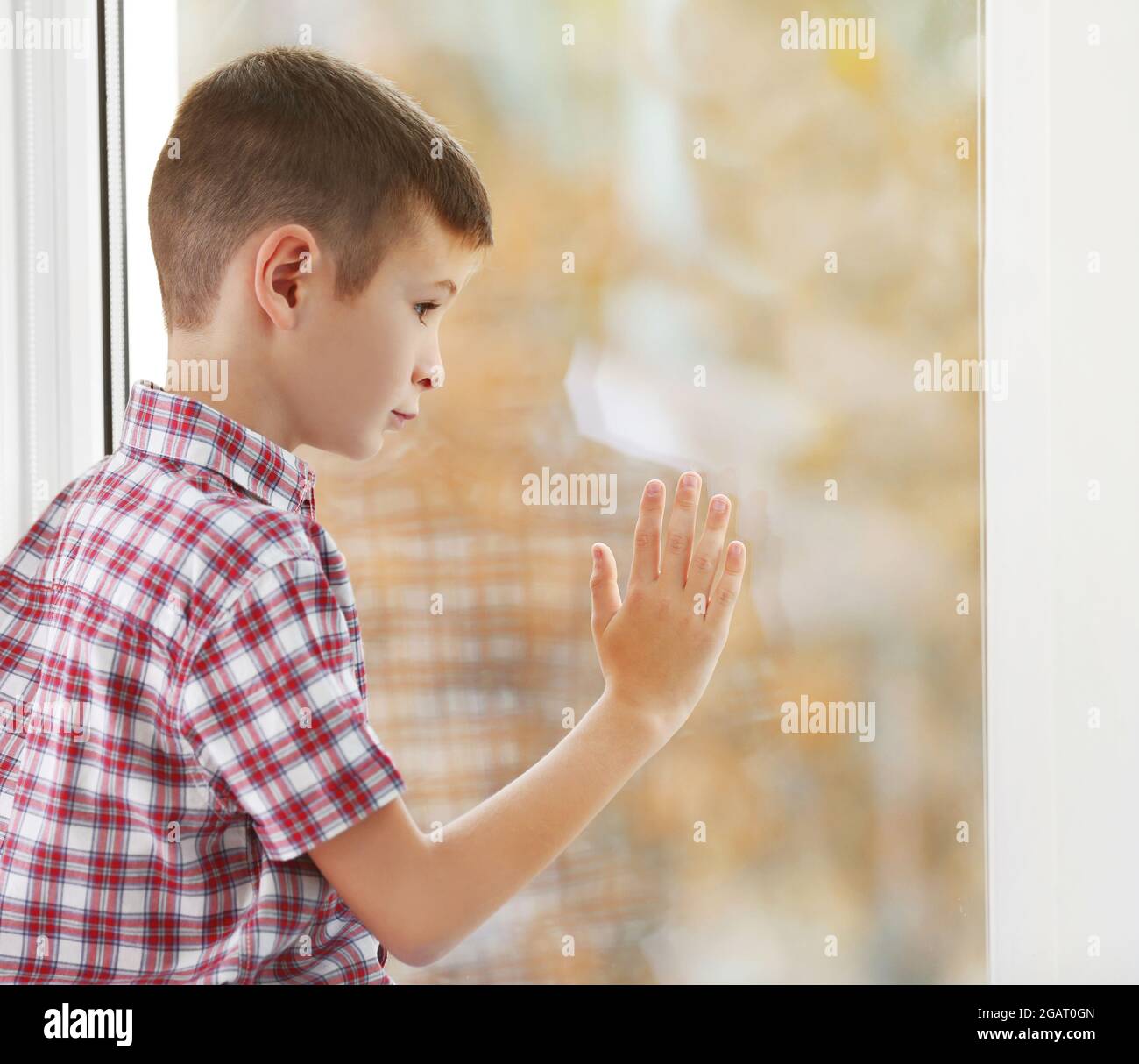 Sad boy sitting near window Stock Photo - Alamy