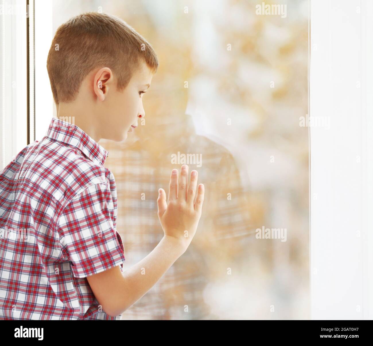 Sad boy sitting near window Stock Photo - Alamy