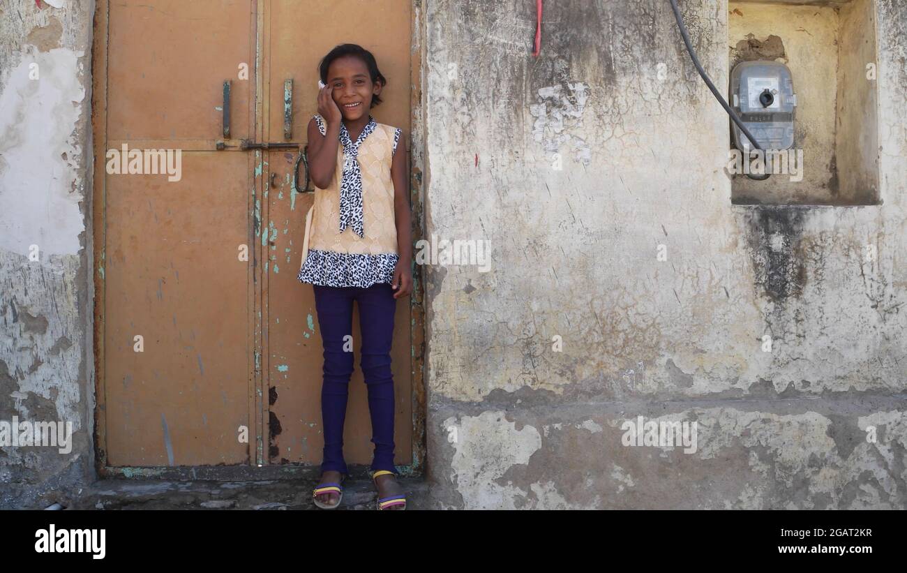 A poor Indian girl standing near an old building and talking on the ...