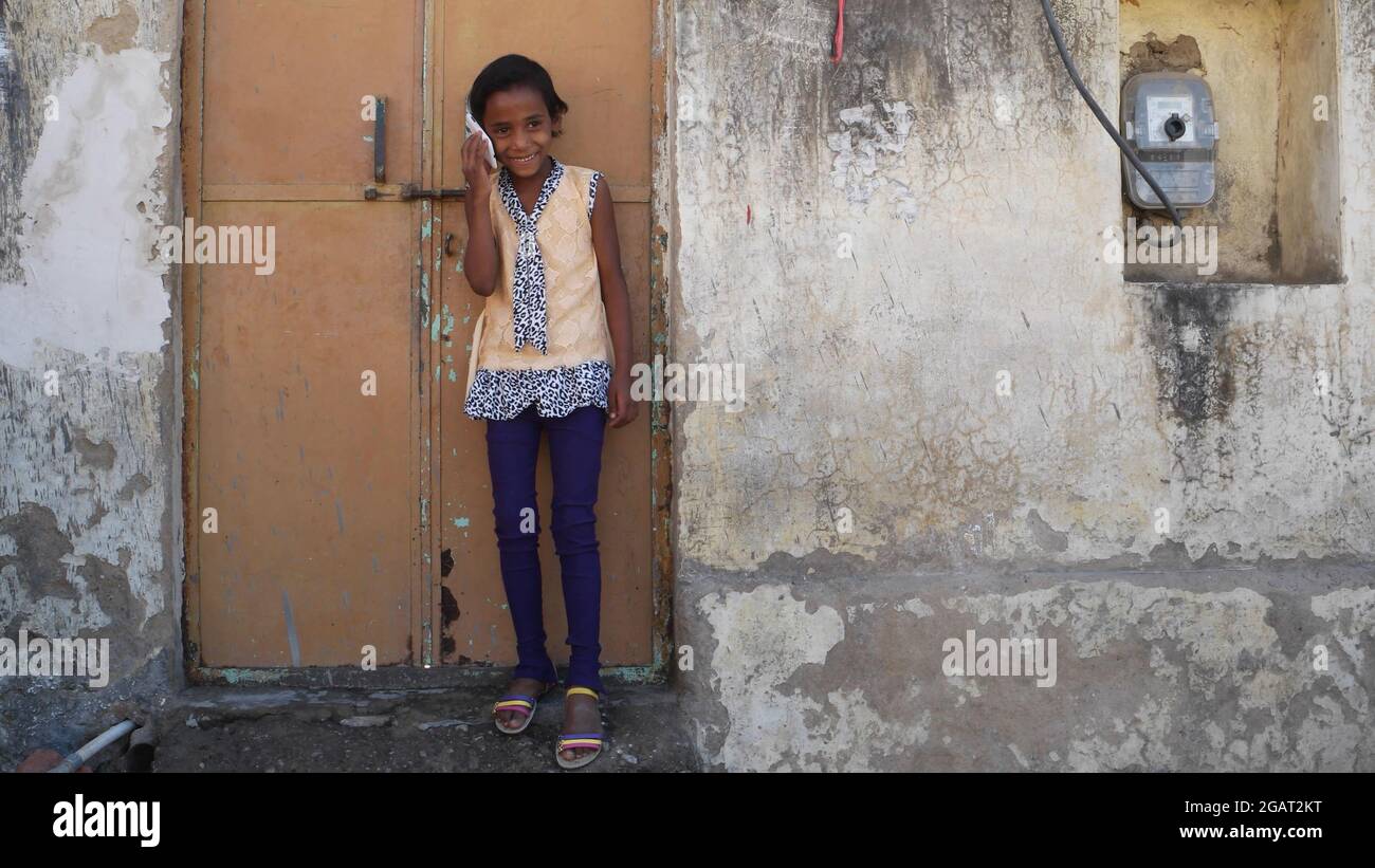 A poor Indian girl standing near an old building and talking on the ...