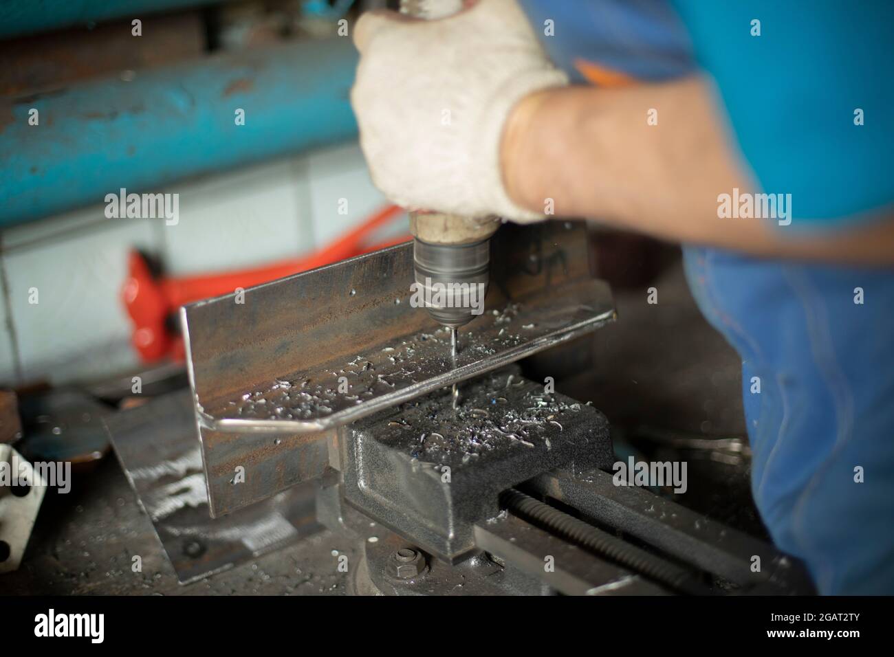 Drills metal with a drill. The man is working. Drilling holes in steel ...
