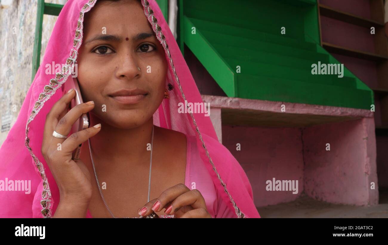 An Indian woman in traditional Indian clothes talking on the phone ...