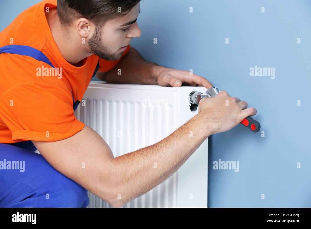 Man repairing battery on blue wall background Stock Photo - Alamy
