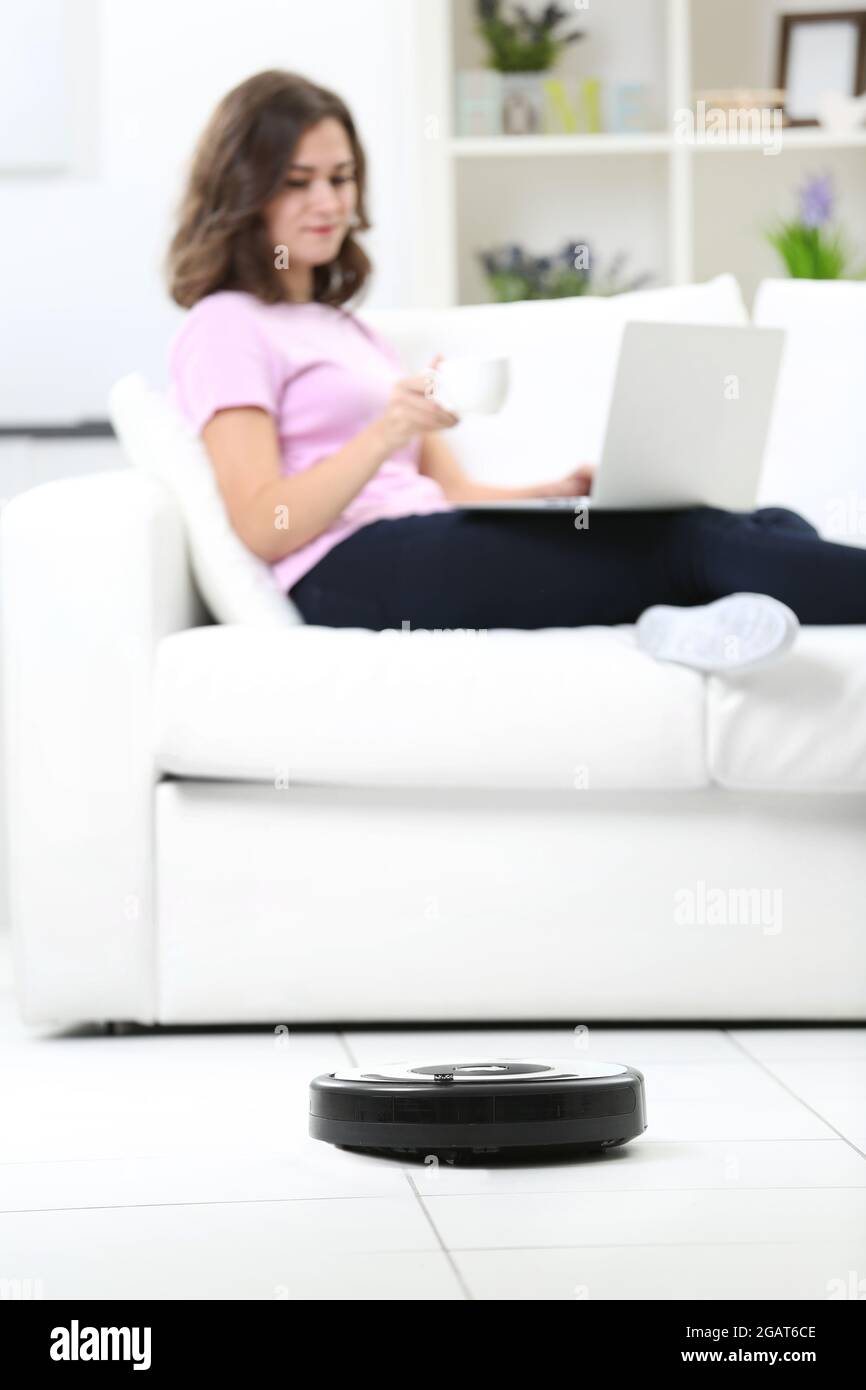 Cleaning concept - automatic robotic hoover clean the room while woman ...