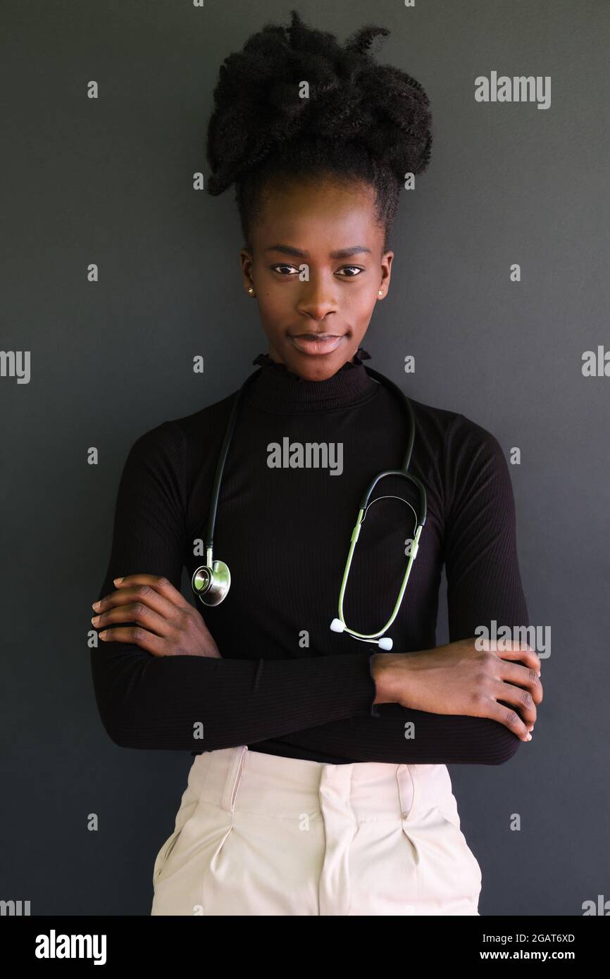 Young female african doctor with stethoscope in a black background ...