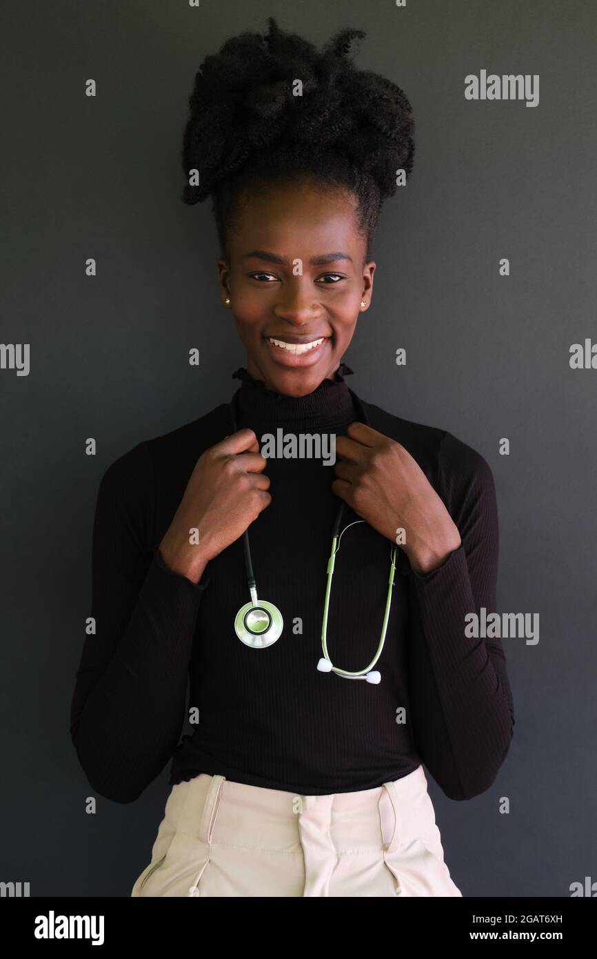 Smiling female african doctor with stethoscope in a black background ...
