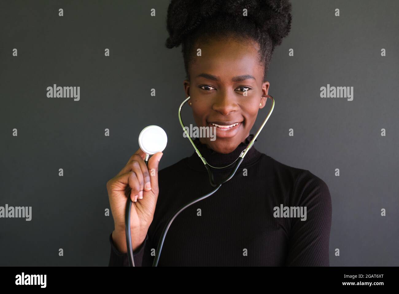 Smiling female african doctor using the stethoscope in a black ...