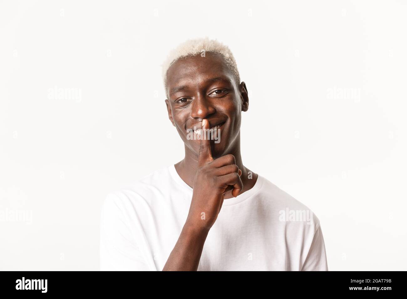 Portrait of happy attractive Black guy with blond hair, showing shush ...