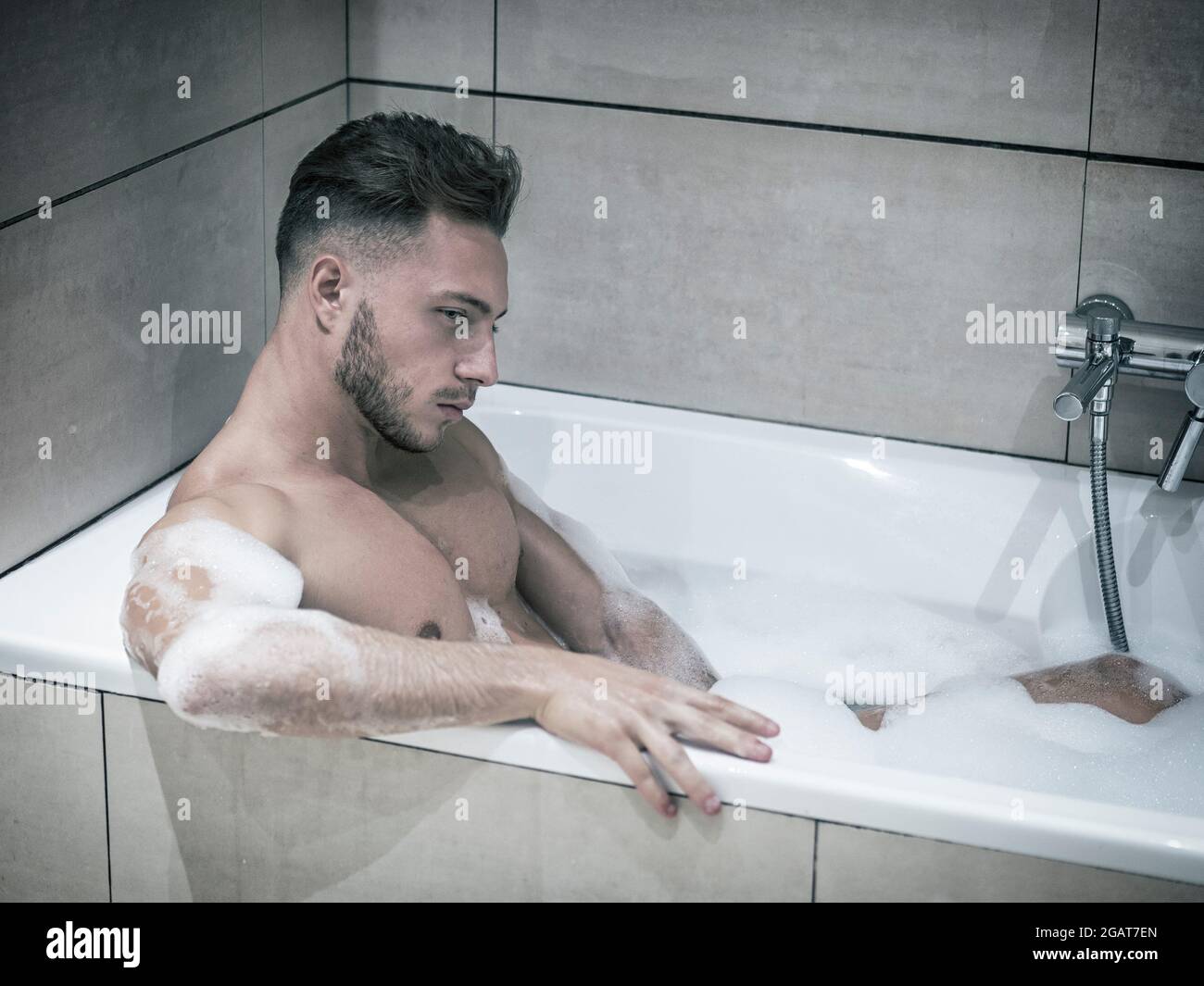 Handsome young man in bathtub at home having bath Stock Photo - Alamy