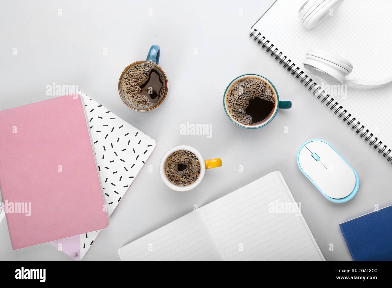 Cups of coffee, PC mouse, headphones and notebooks on grey background ...