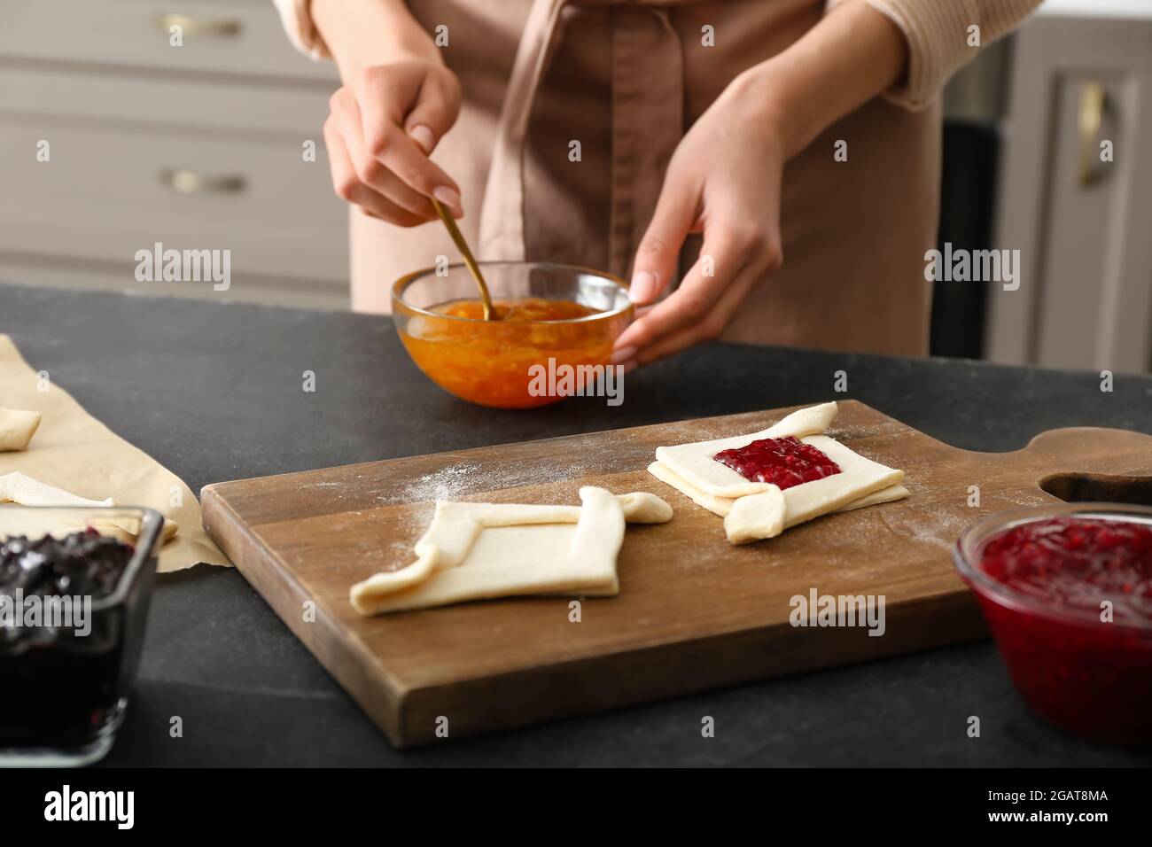 Woman filling Danish pastry with fruit jam on kitchen table Stock Photo ...