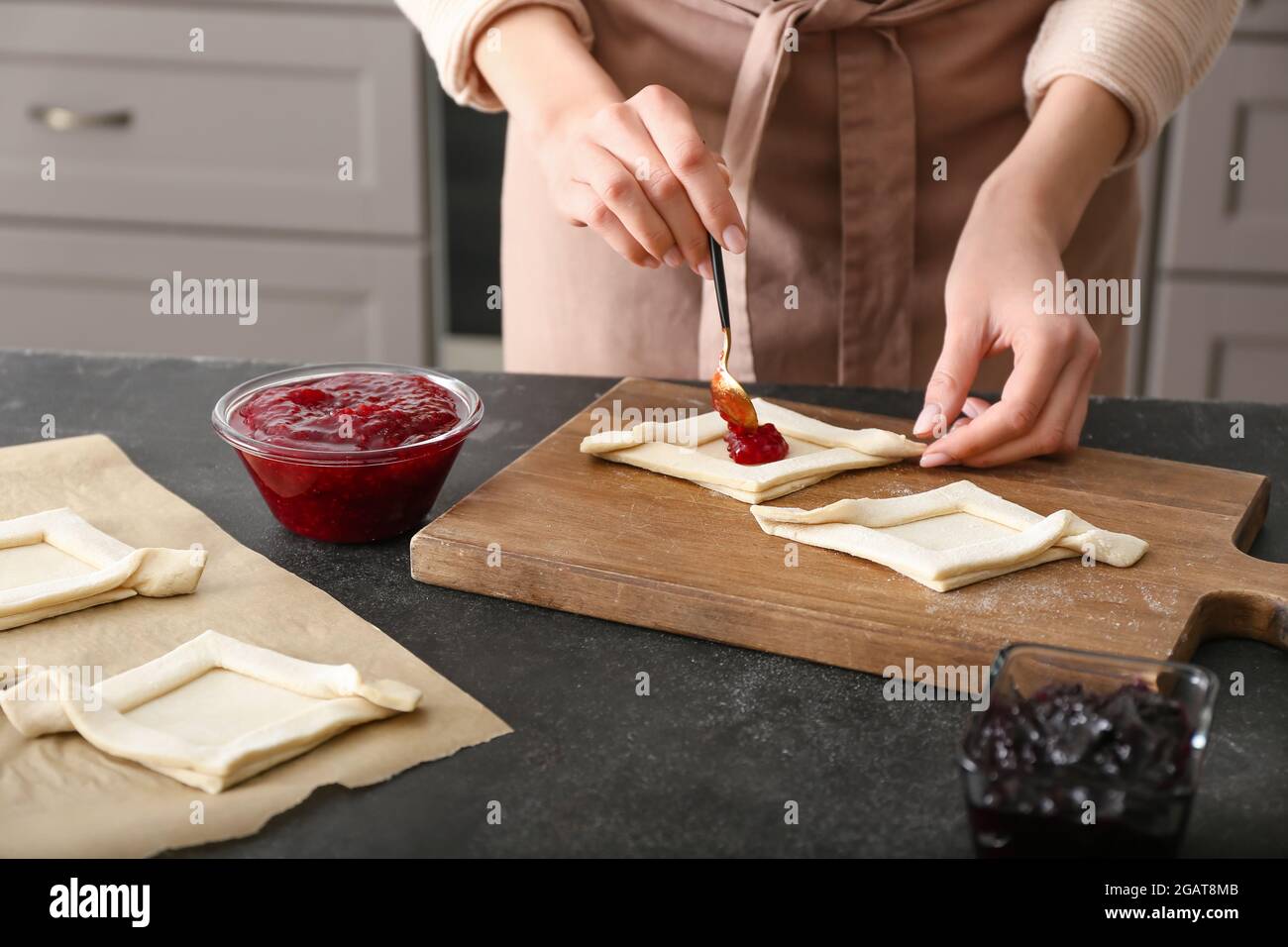 Woman filling Danish pastry with fruit jam on kitchen table Stock Photo ...