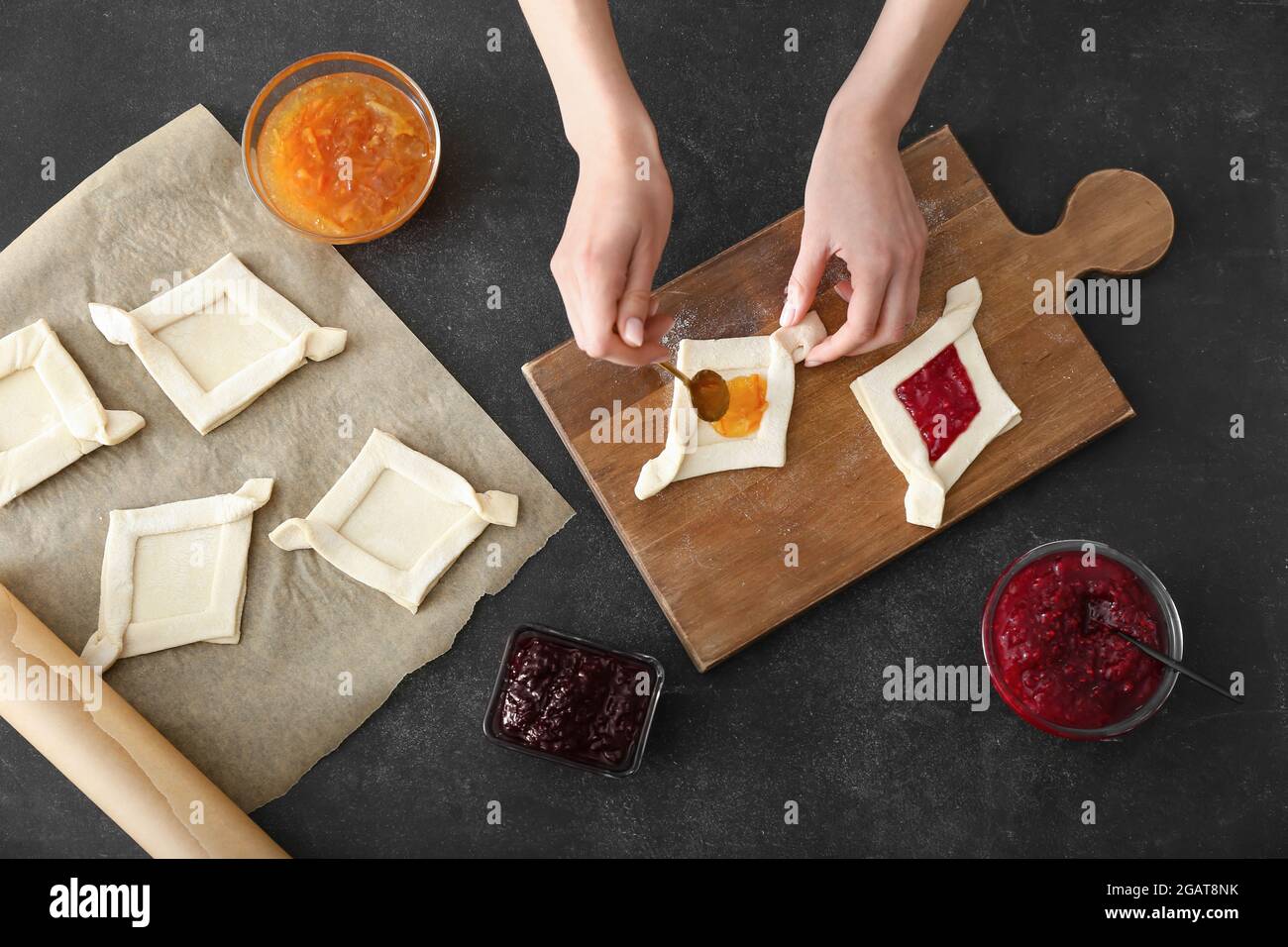 Woman filling Danish pastry with fruit jam on kitchen table Stock Photo ...